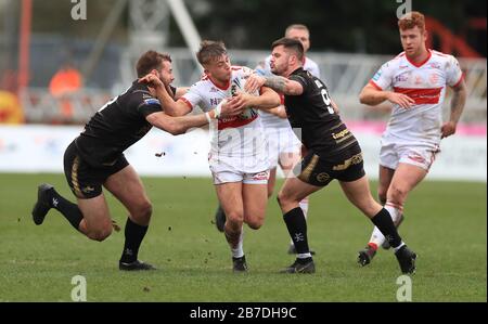 Hull KR's Mikey Lewis is tackled by Hull FC's Aidan Sezer (left) and ...
