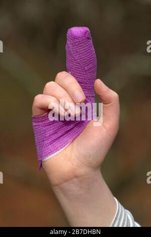 Closeup of a young woman's sutured finger wrapped in winding layers of ...