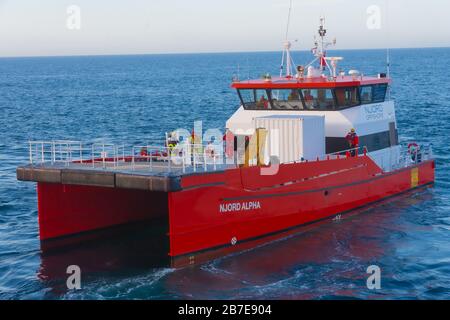 Offshore wind farm, crew transfer vessel docked on landing station ...
