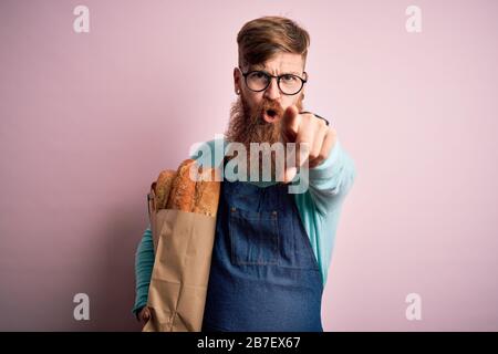 Irish redhead baker man with beard holding groceries paper bag of bread ...