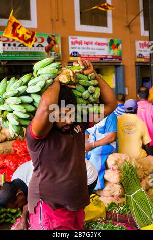 Men carrying bunches of green bananas and other products to local ...