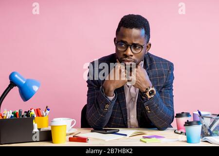 Portrait of tired unhappy young dark skinned manager sitting at ...