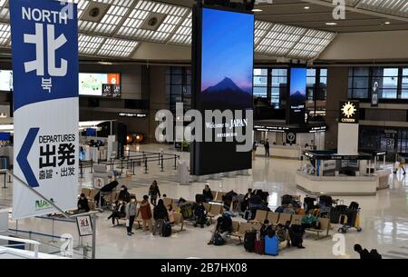 Travelers wear masks as they wait in a line for a TSA security check ...