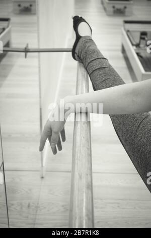 A ballerina stretches with her leg on the barre, gracefully resting her ...
