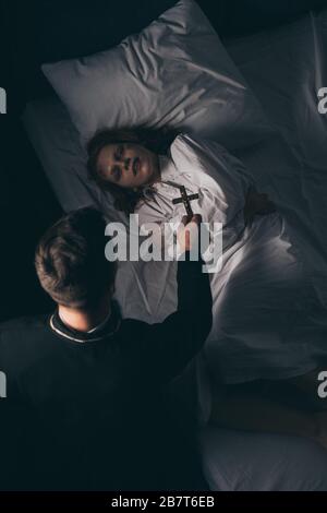 exorcist holding cross over creepy screaming demon in bed Stock Photo ...