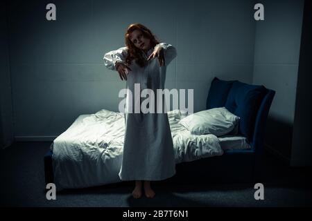 crazy female demon in nightgown sitting on bed Stock Photo - Alamy