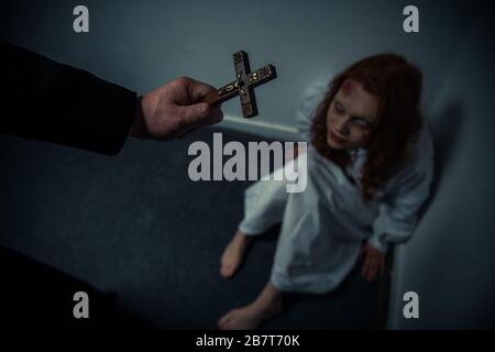 exorcist holding cross in front of obsessed girl in bed Stock Photo - Alamy