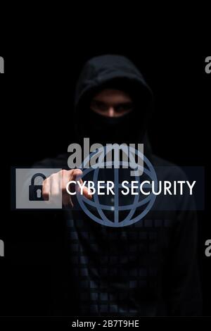 selective focus of hacker in hood pointing with finger at padlock illustration on black Stock ...