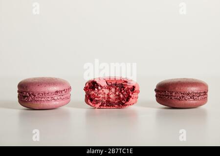 delicious whole and one bitten red french macaroons on white background ...