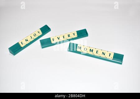 Scrabble tiles spell out Enjoy Every Moment. Motivational quote ...