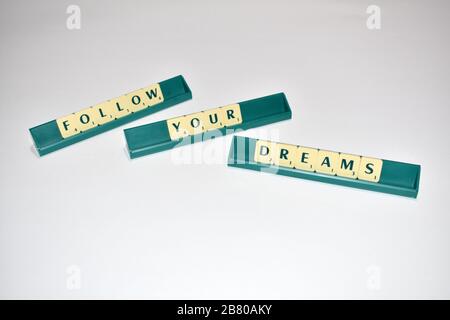 Scrabble tiles spell out Follow Your Dreams. Motivational quote ...