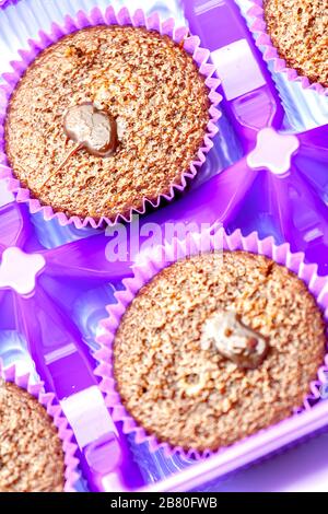 Chocolate muffins in purple paper cups on wooden board, closeup view ...