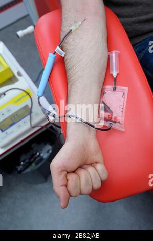 Arm on an armrest, hypodermic needle, tubes, container with blood ...