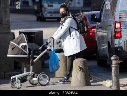 A woman wearing a protective mask walks past a graffiti in Navi Mumbai ...