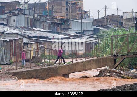 People using a footbridge to cross the Mathare river, Mathare, Nairobi ...