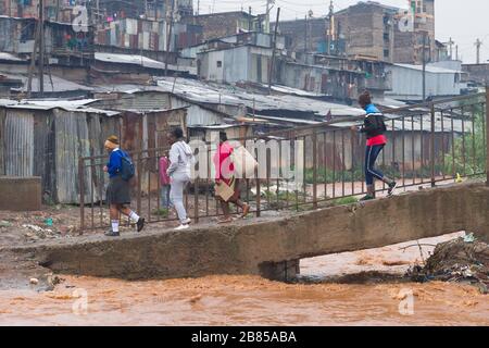 People using a footbridge to cross the Mathare river, Mathare, Nairobi ...