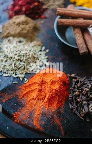 Grounded chili pepper on black rustic surface, surrounded by spices ...
