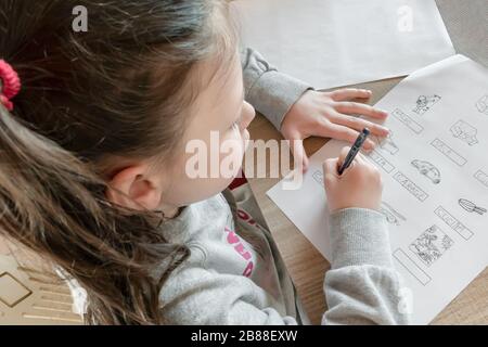 Cute little girl doing homework, reading a book, coloring pages ...