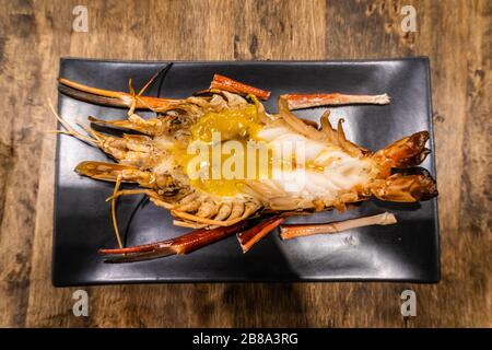 Fresh grilled river prawns with a lot of fat on the head resting on a ...