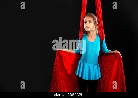 Little acrobat girl shows an acrobatic performance on an aerial hoop ...