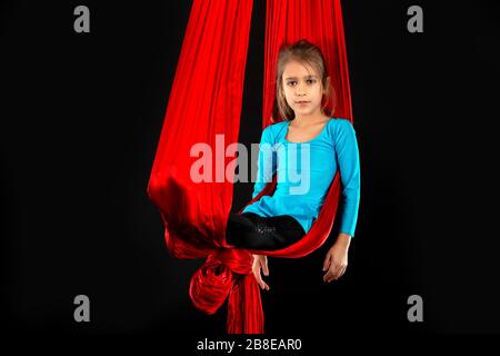 Little acrobat girl shows an acrobatic performance on an aerial hoop ...