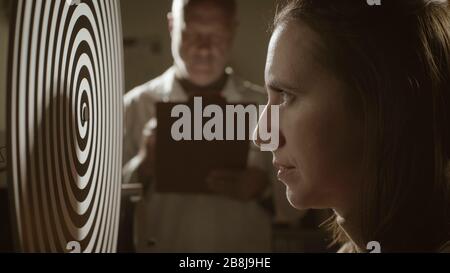 Scientist doing hypnosis experiments in the vintage style lab, a woman ...