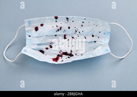 Hemoptysis, coronavirus, protective surgical mask with blood on red ...