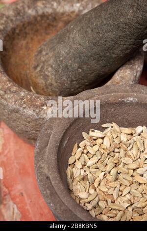 Display of cardamon pods or seeds, with grey stone mortar and pestle ...