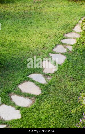 Garden stone path with grass growing up between and around stones ...
