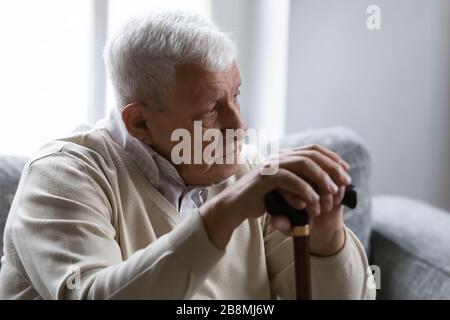 senior man with parkinson disease sitting on couch in knitted cardigan ...