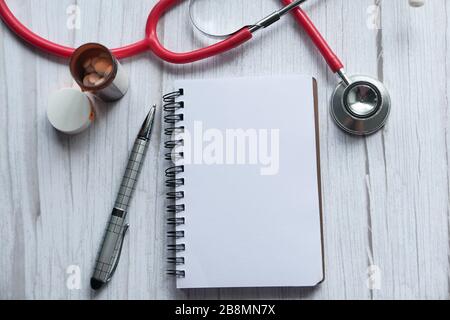 Stethoscope, sticky notes, notepad or notebook, pen and vase on blue ...