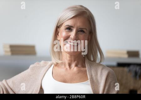 Closeup portrait of happy pleasant mature woman enjoying walk in yellow ...