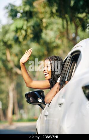Young woman waving through window Stock Photo - Alamy