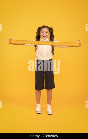 What a long ruler. Surprised little student holding rigid wooden ruler ...