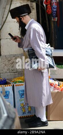 Orthodox Jewish man using a mobile phone in a rowing boat, Hollow Ponds ...