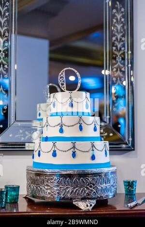 A vertical shot of a three-layered wedding cake topped with love text ...