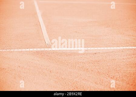 Sand and gravel tennis court sub-base. Blurred background. Coral tones ...