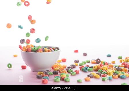 bright multicolored breakfast cereal falling in bowl isolated on white ...