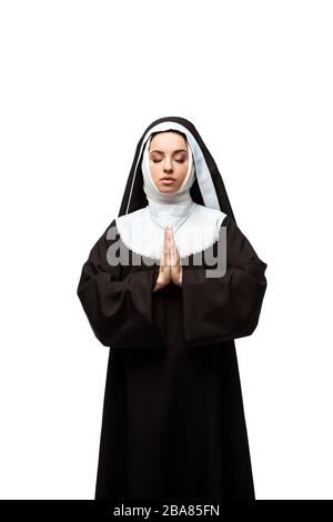 attractive nun praying with closed eyes and hands together isolated on ...
