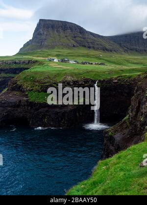 Scenic view of sea and Mulafossur waterfall under cloudy sky Stock ...