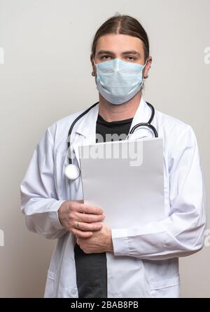 Male Doctor Wearing White Coat Sitting At Desk Looking At CT Or MRI ...