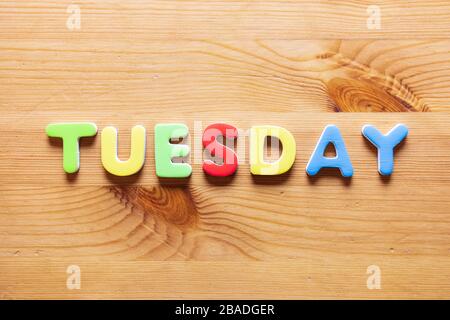 Tuesday word written with colorful letters on white marble stone ...