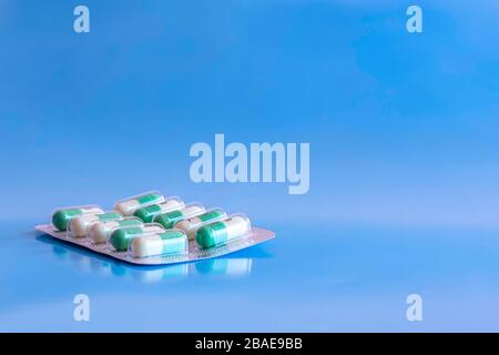One blister of antidepressant tablets on blue, shiny background with ...