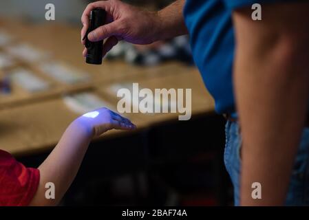 teacher checking child's hands with blacklight after hand washing Stock ...
