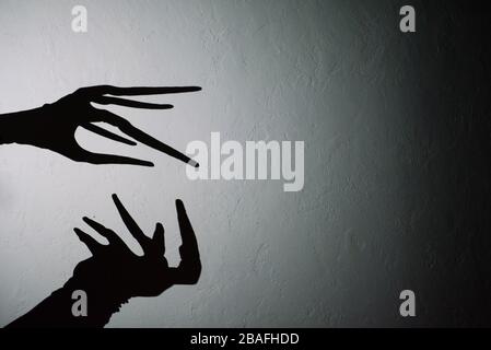 shadow of creepy hands with long fingers against white wall Stock Photo ...