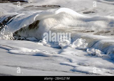 a close-up of a small wave with foam on the shore sand, seaside Stock ...