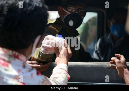 An army soldier distributes hand sanitizer to the poor people amid ...