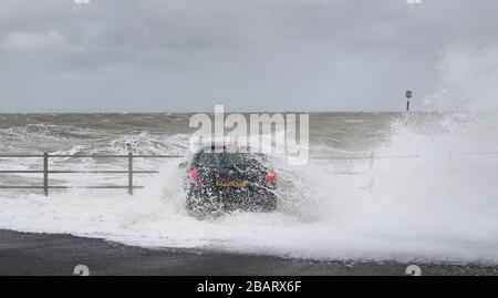 Waves crash over a car on the seafront during windy conditions in ...