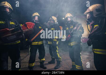 Group of firefighters with chainsaw and sledge hammer practicing in the ...