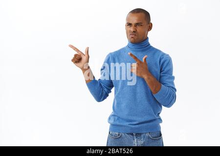 Portrait of frowing young man pointing fingers up. People, emotions ...